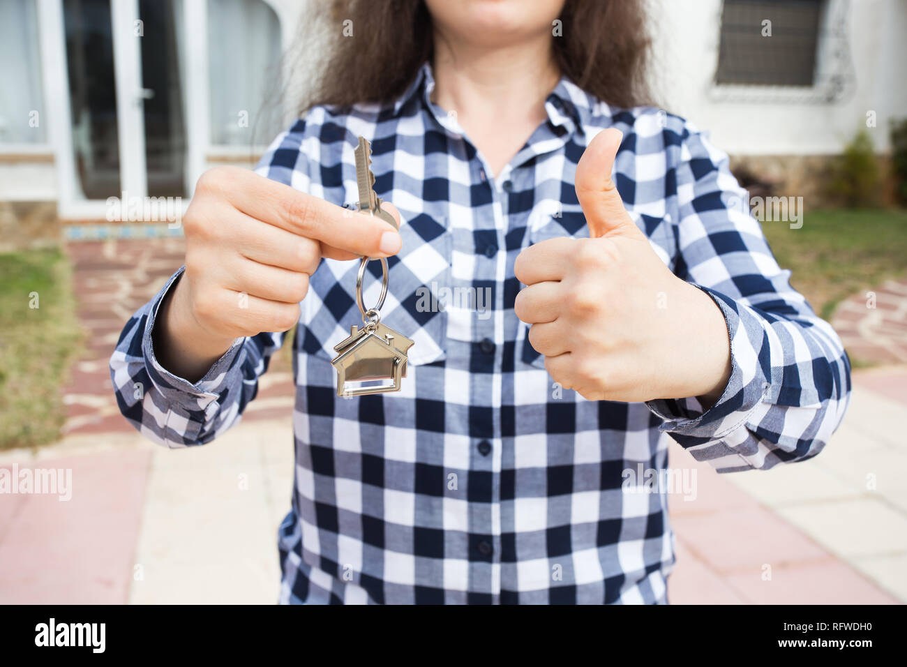 Close up of woman holding key with a keychain in the shape of the house ...