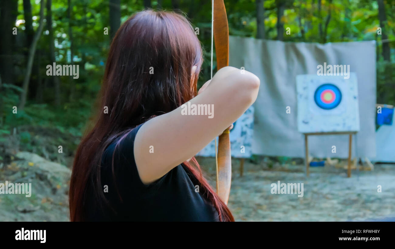 Medieval female archer shooting targets with wooden bow at historical ...