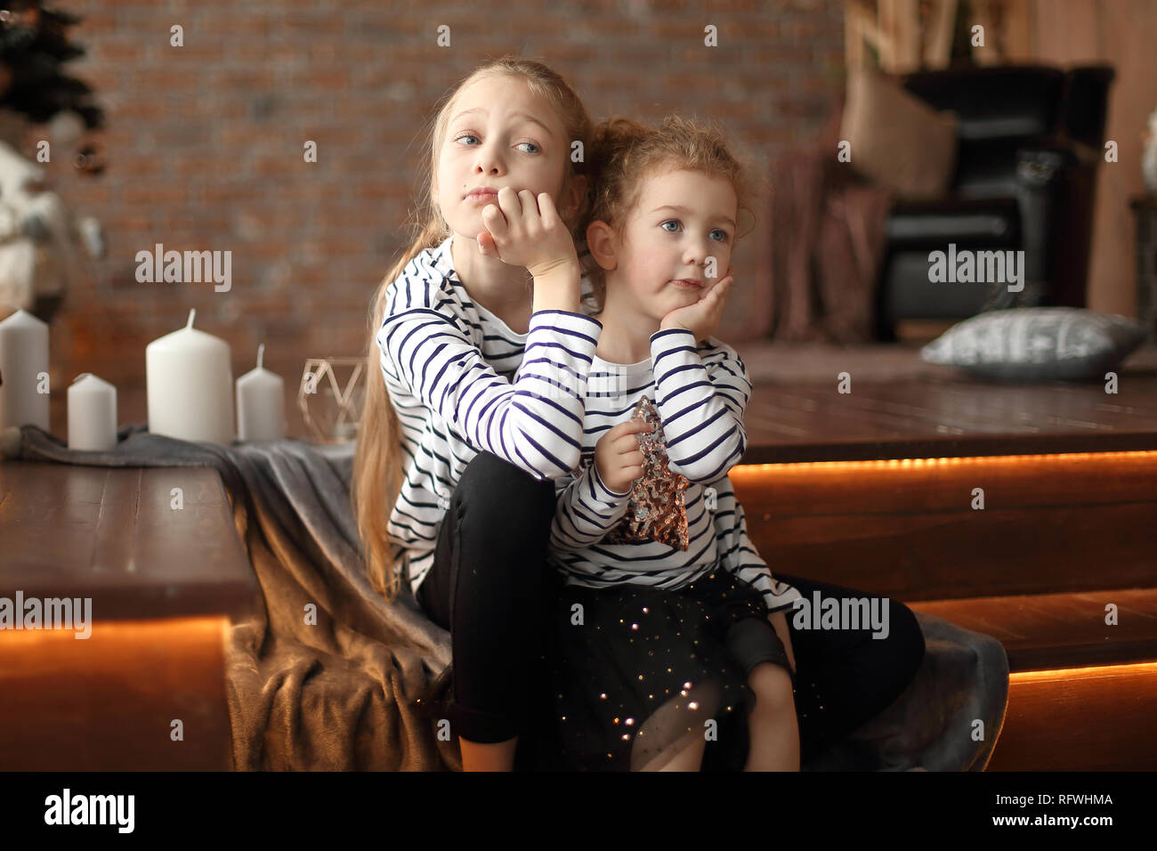 two little sisters talk sitting in a cozy living room Stock Photo - Alamy
