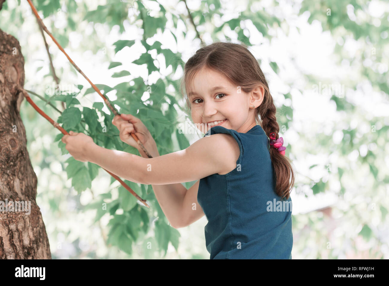 Portrait of a cute girl sitting on a big tree on a Sunny day Stock ...