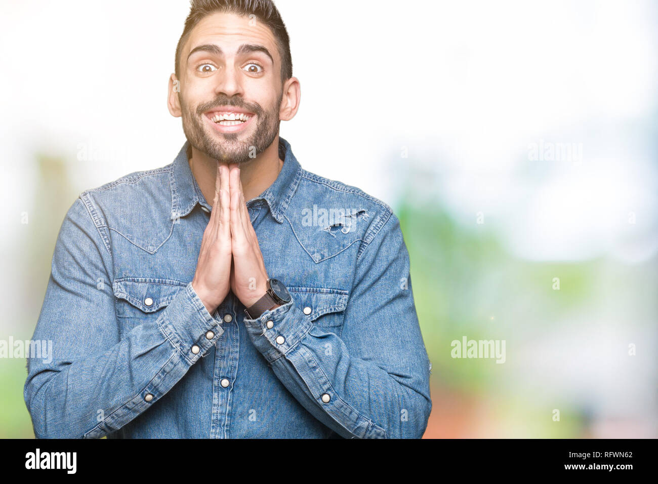 Young handsome man over isolated background praying with hands together ...