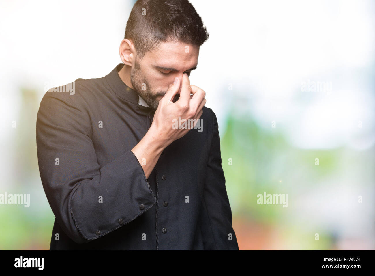Young Christian priest over isolated background tired rubbing nose and ...