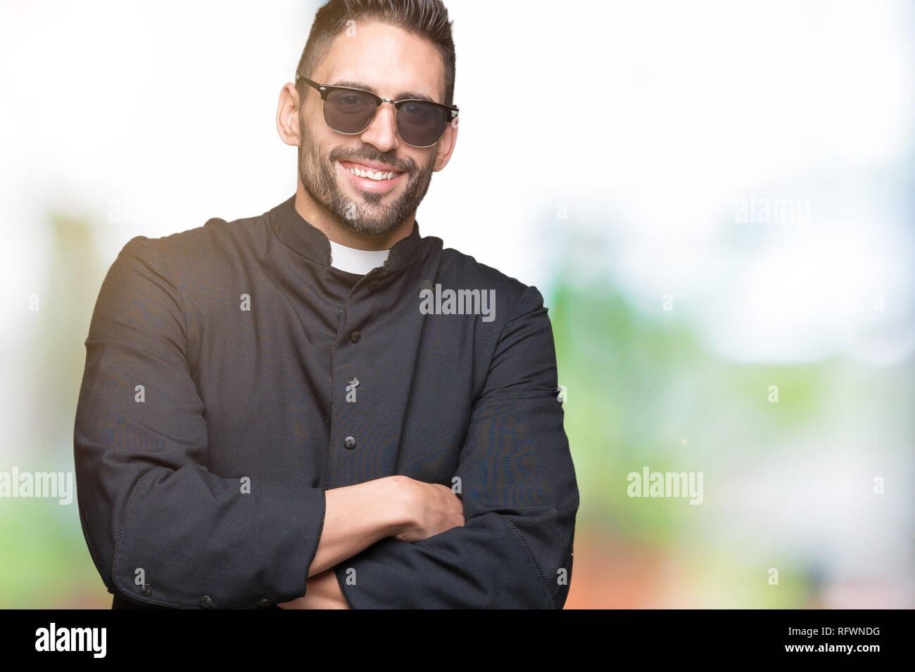 Young Christian priest wearing sunglasses over isolated background ...