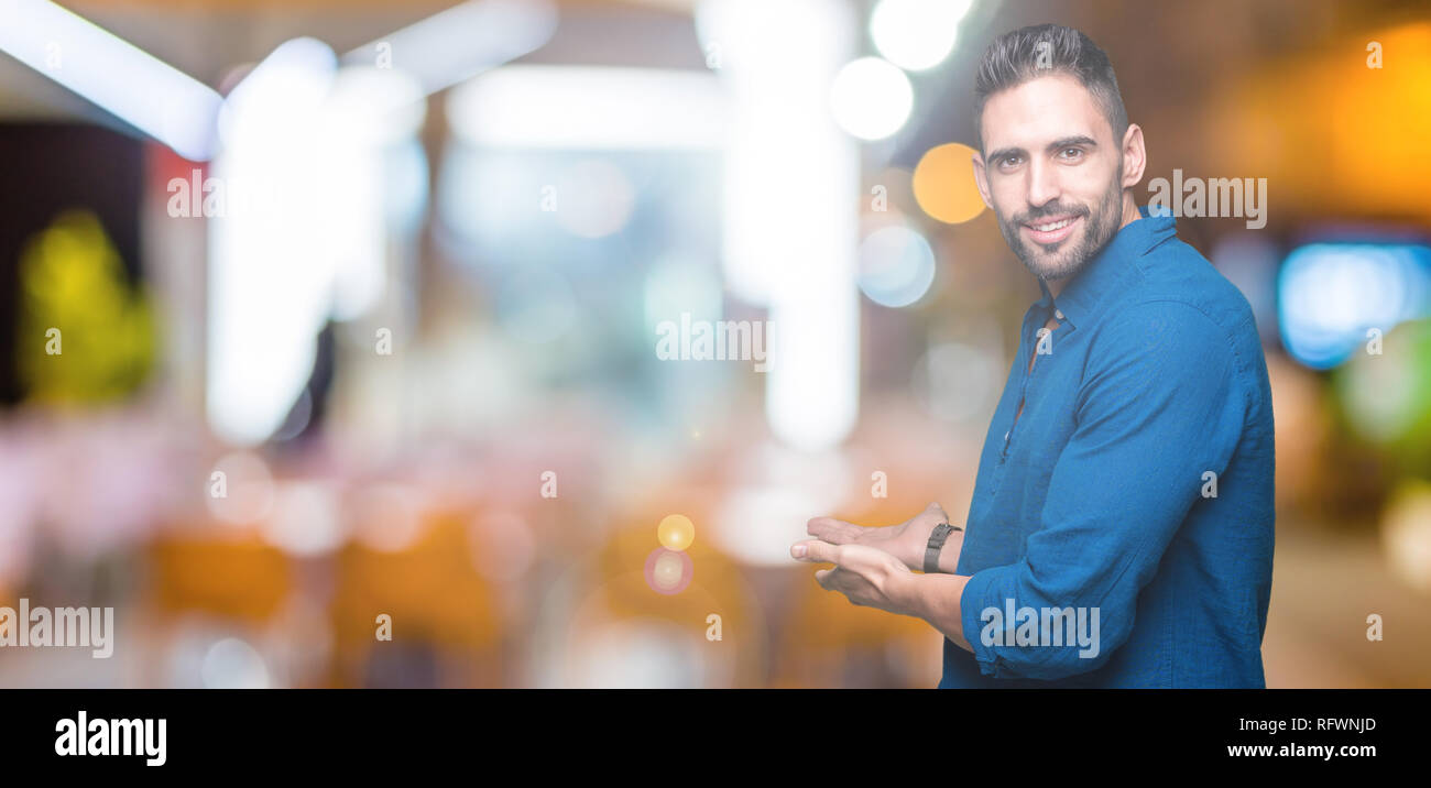Young handsome man over isolated background Inviting to enter smiling ...