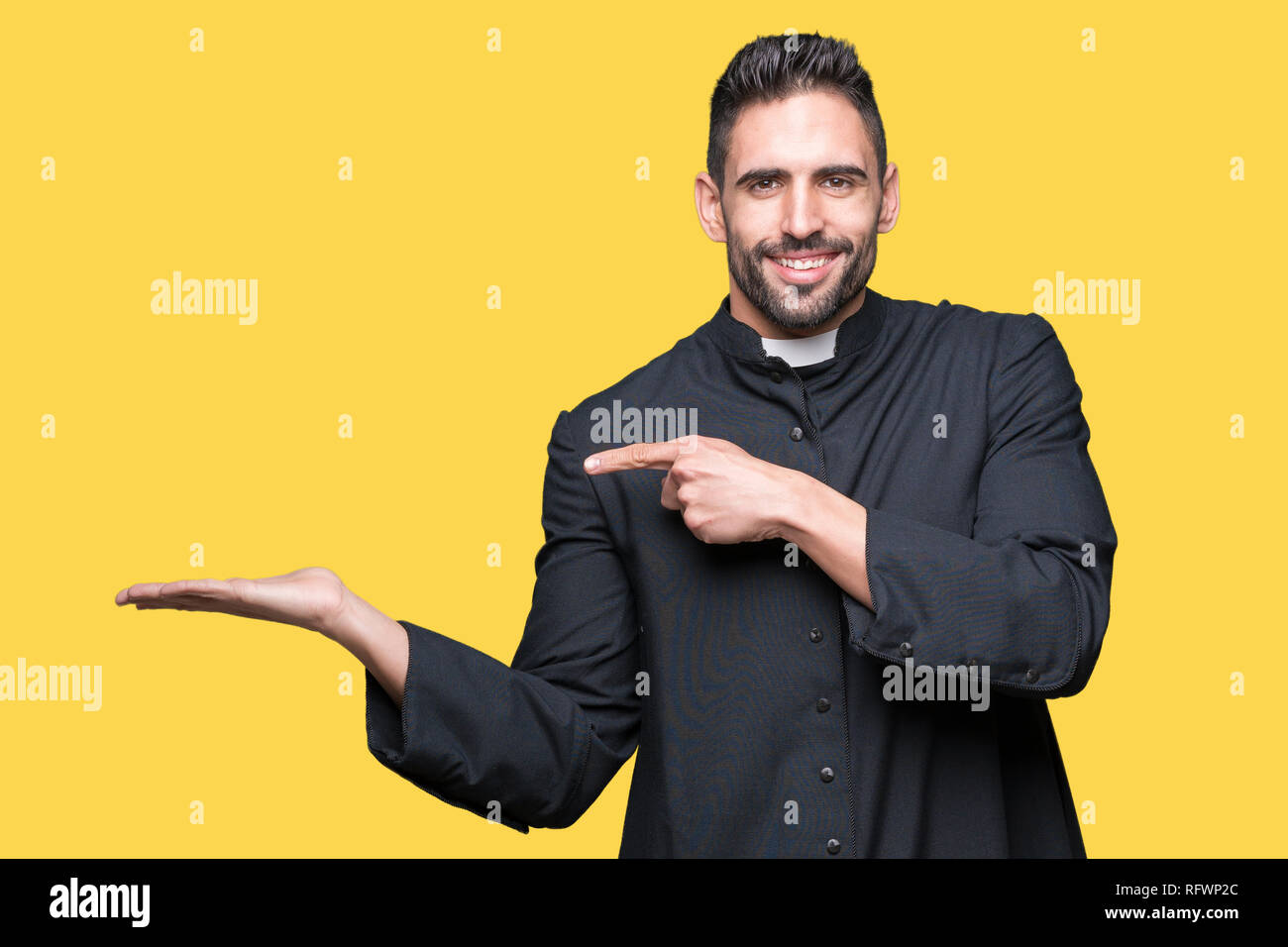Young Christian priest over isolated background amazed and smiling to ...