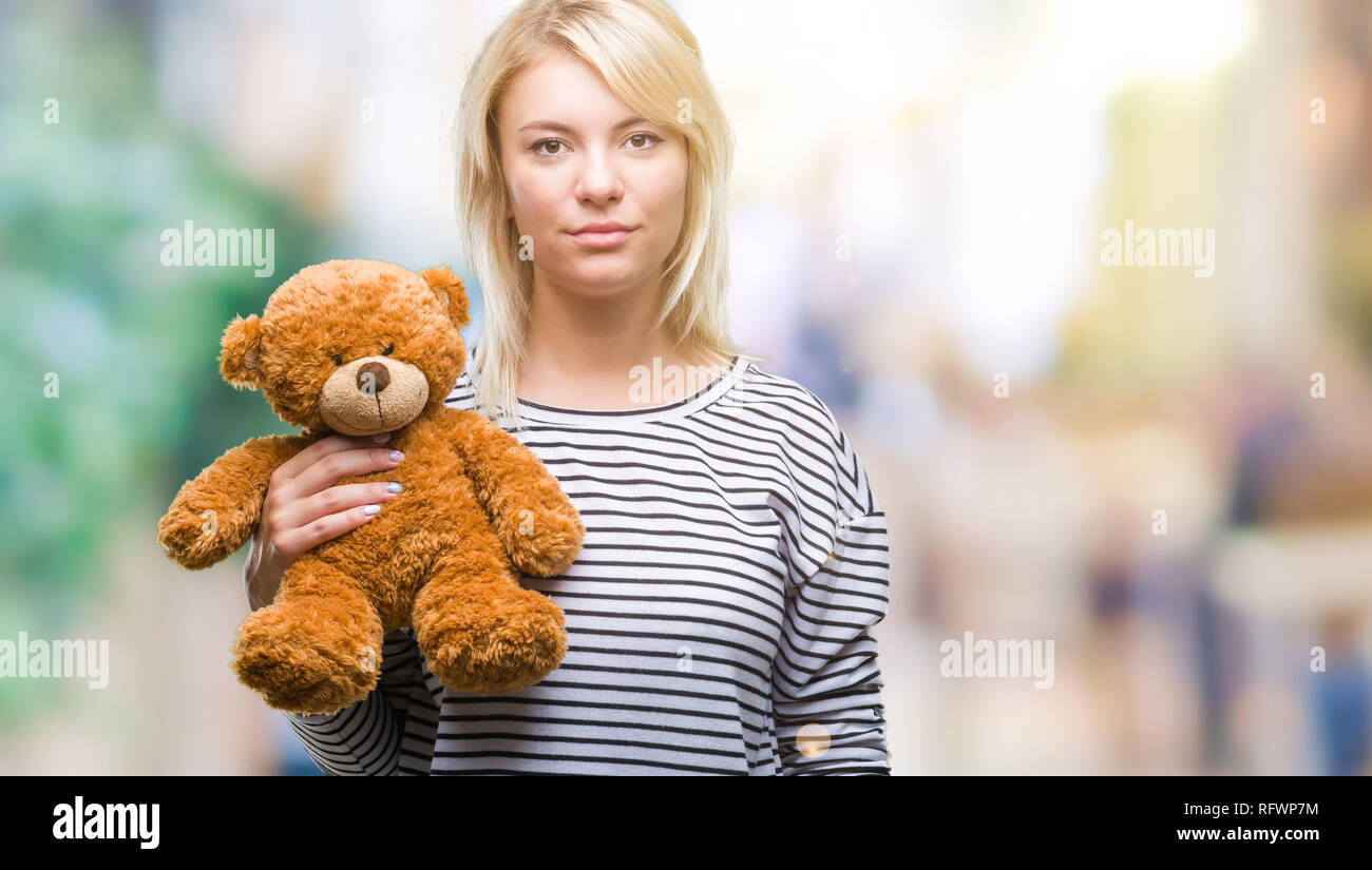 Young beautiful blonde woman holding teddy bear plush over isolated ...