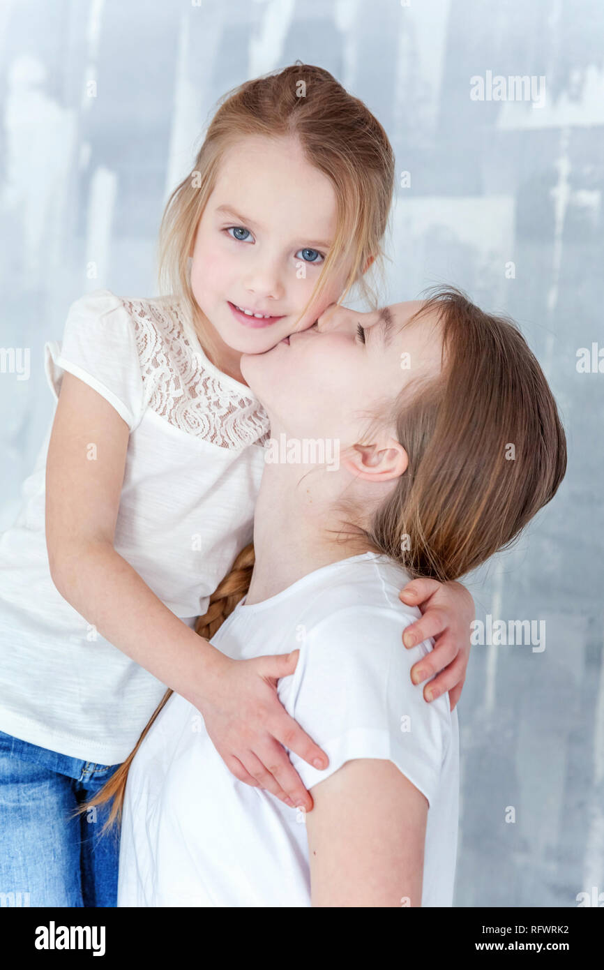 Two happy kids standing against grey textured wall background and ...