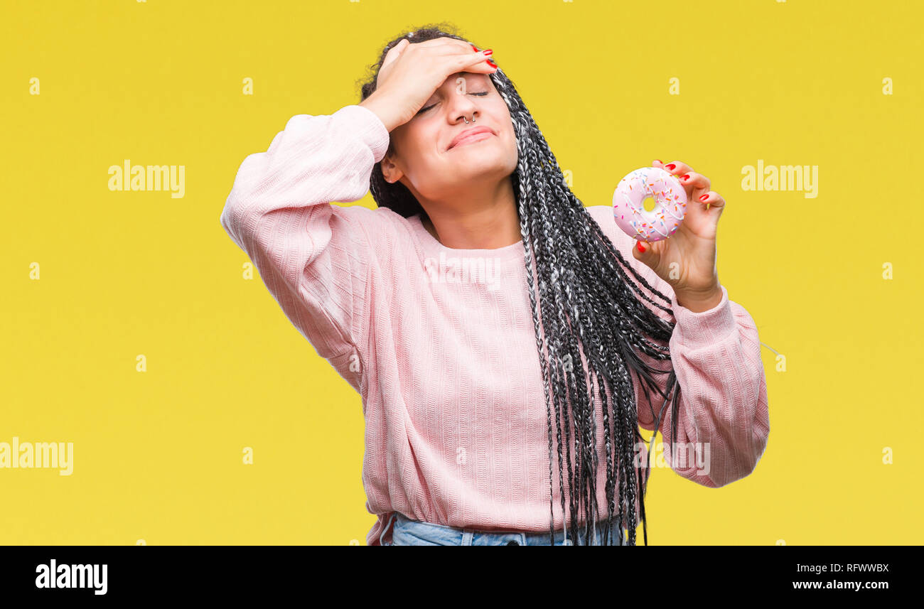 Young african american girl eating pink donut over isolated background ...