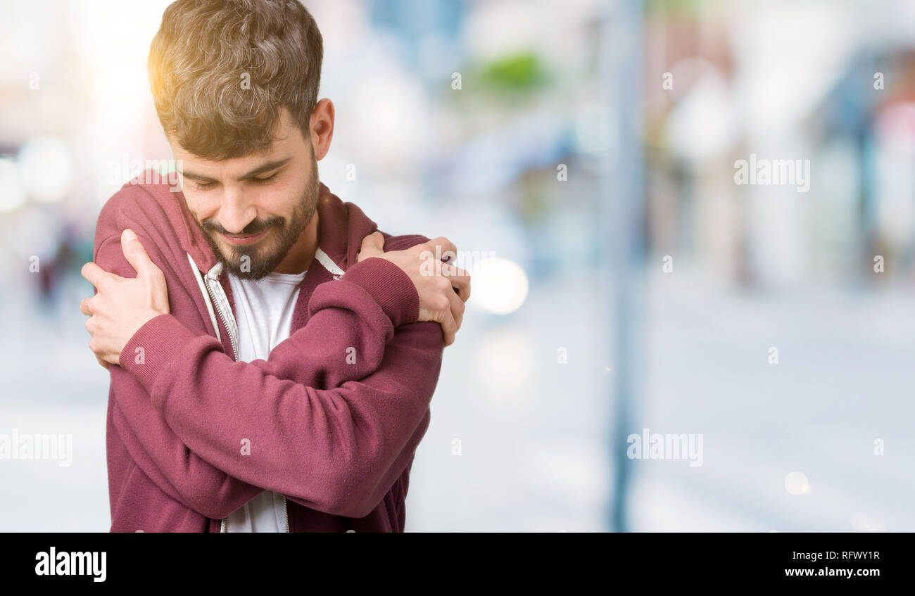 Young handsome man over isolated background Hugging oneself happy and ...