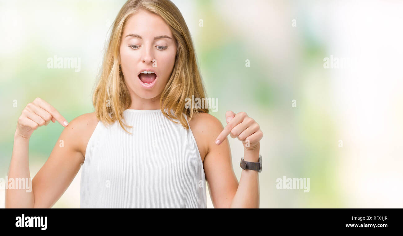 Beautiful young elegant woman over isolated background Pointing down ...