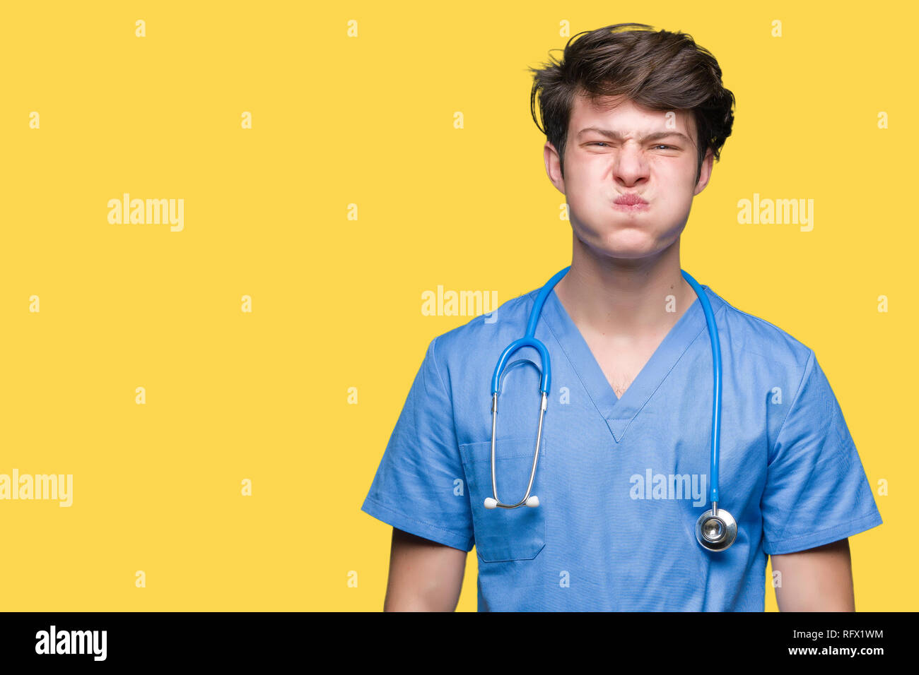 Young doctor wearing medical uniform over isolated background puffing ...