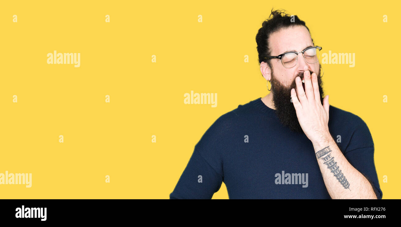 Young hipster man with long hair and beard wearing glasses bored ...