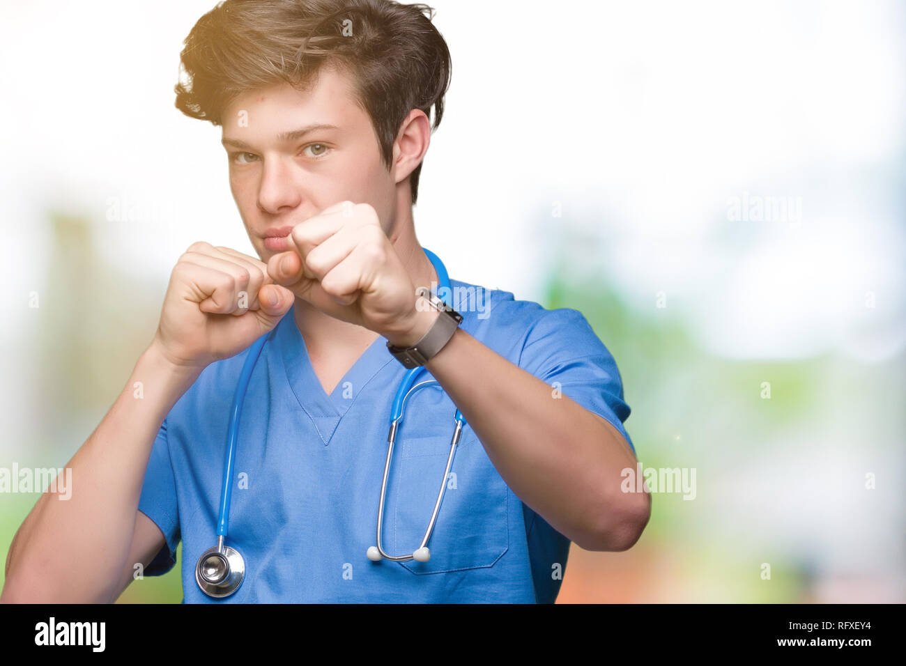 Young doctor wearing medical uniform over isolated background Punching ...
