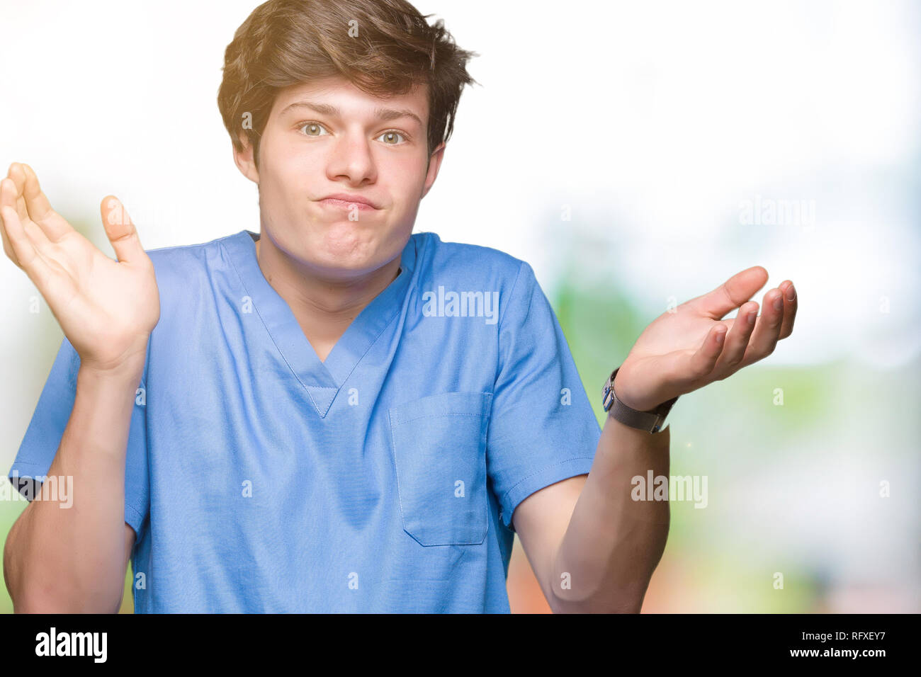 Young doctor wearing medical uniform over isolated background clueless ...