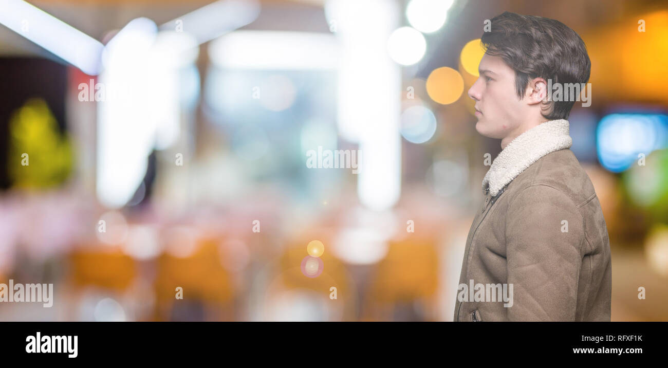 Young handsome man wearing winter coat over isolated background looking ...