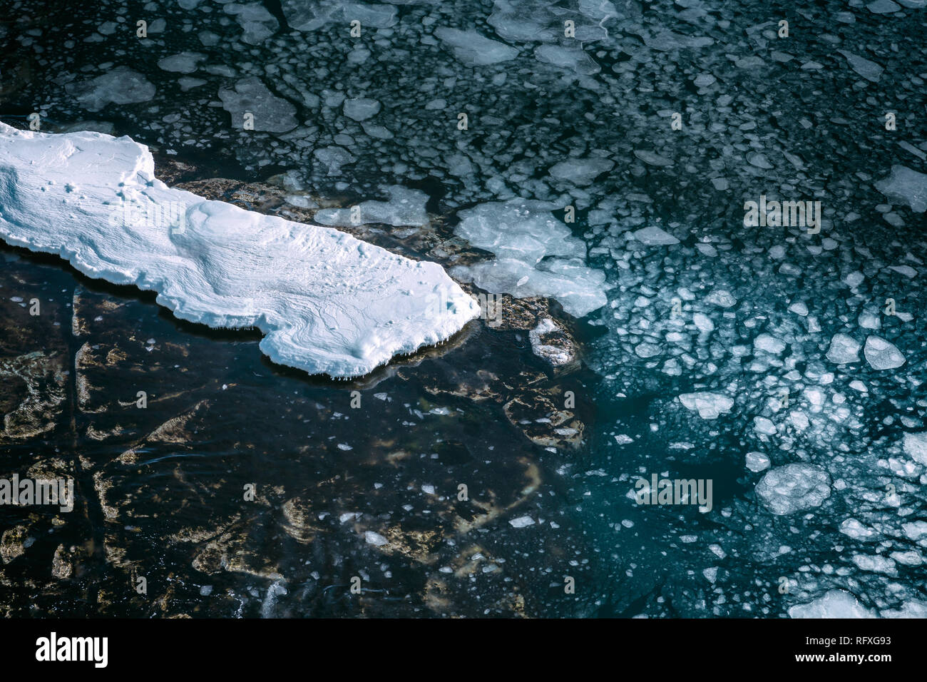 Blue sea surface with thin ice texture and snow on the rocks Stock ...
