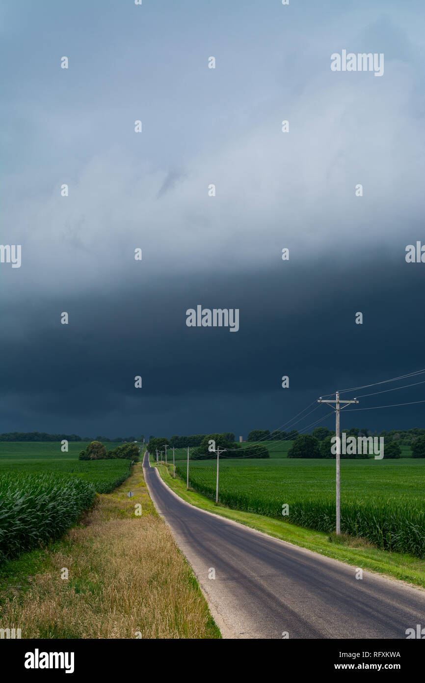 Incoming thunderstorm clouds with road going through rural countryside ...