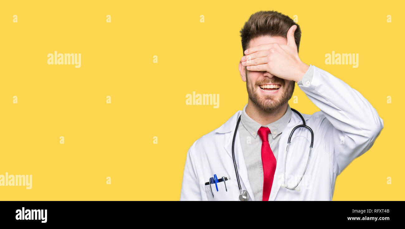 Young handsome doctor man wearing medical coat smiling and laughing ...