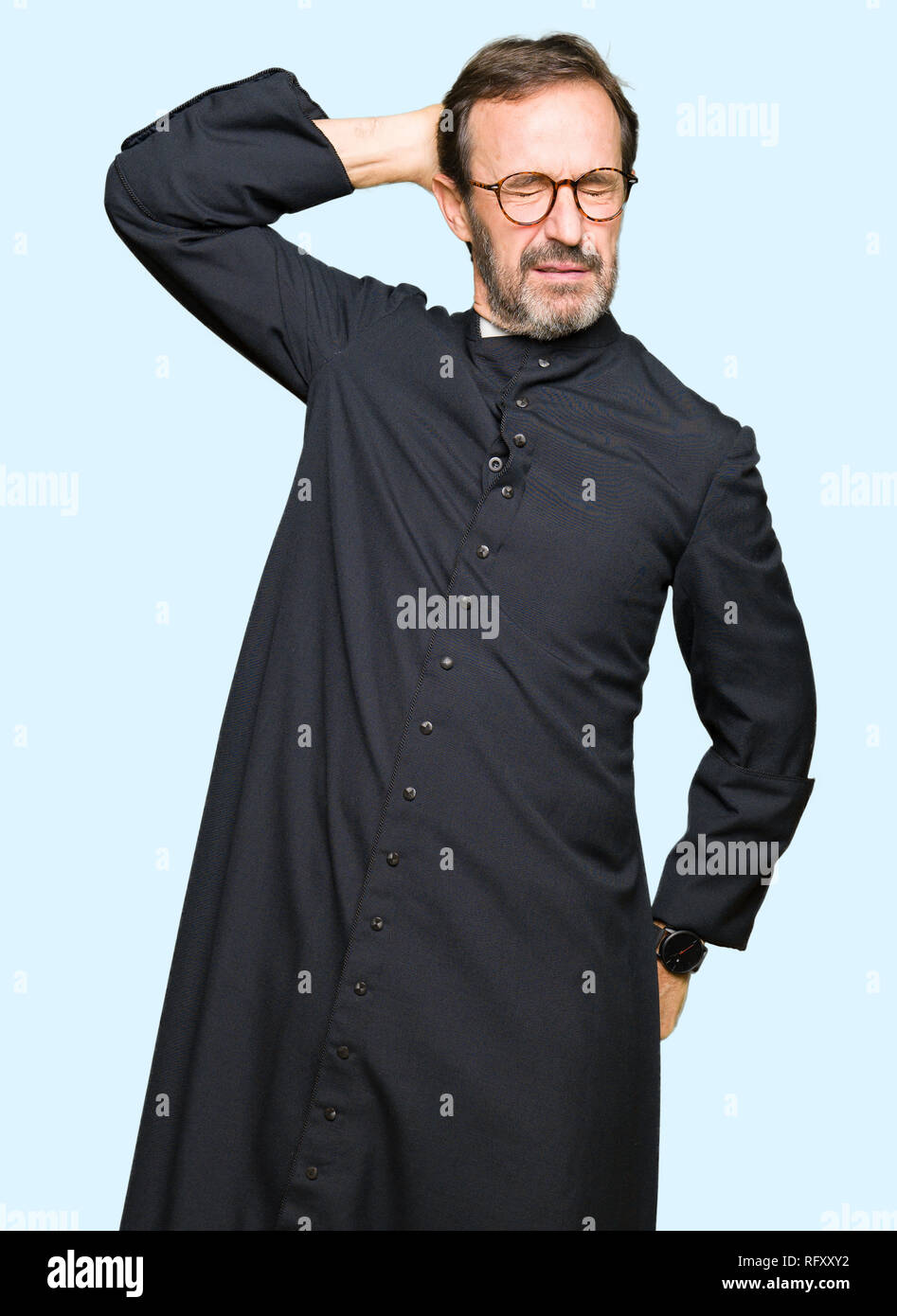 Middle age priest man wearing catholic robe stretching back, tired and ...