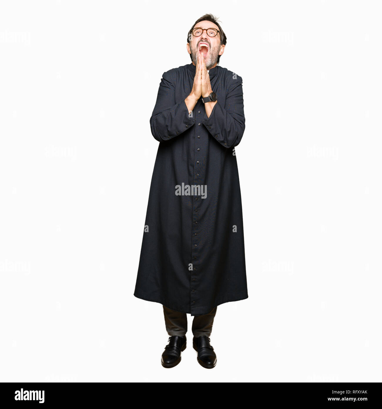 Middle age priest man wearing catholic robe begging and praying with ...