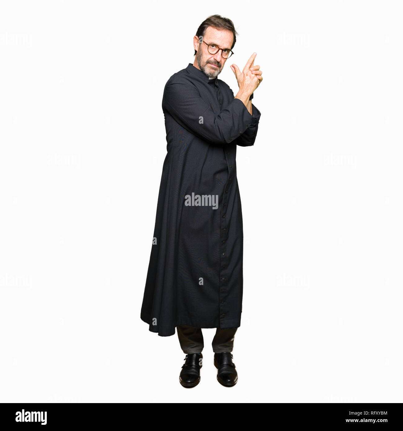 Middle age priest man wearing catholic robe Holding symbolic gun with ...