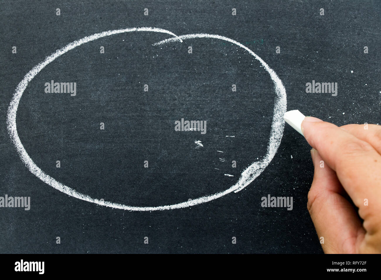 Man hold white chalk to write something on black board with circle ...
