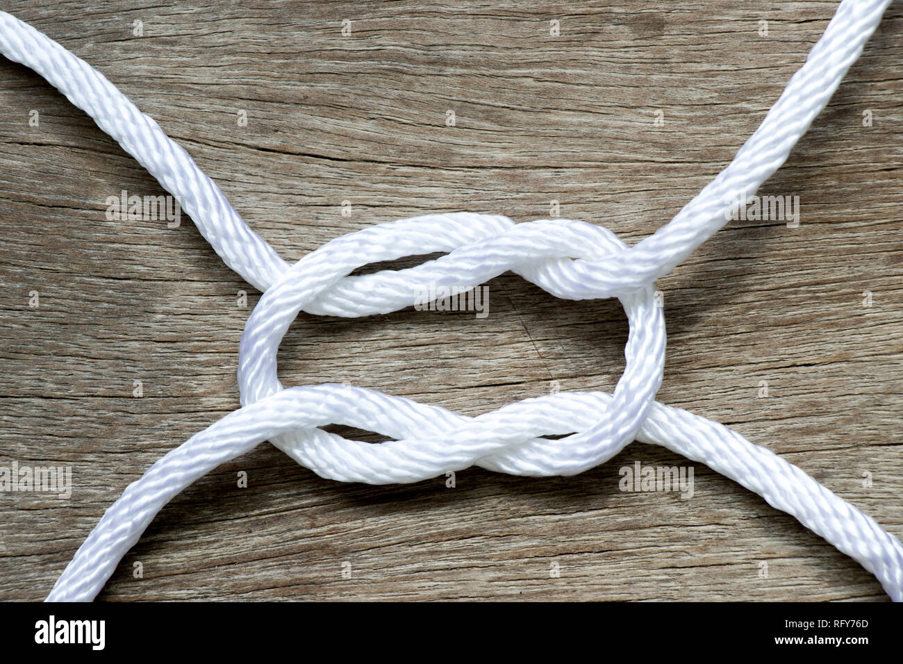 White rope in reef knot shape on wood background Stock Photo - Alamy