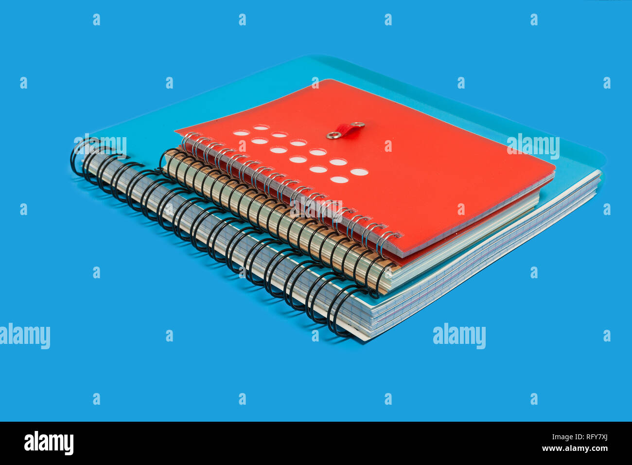 pile of notebooks on a blue background Stock Photo - Alamy