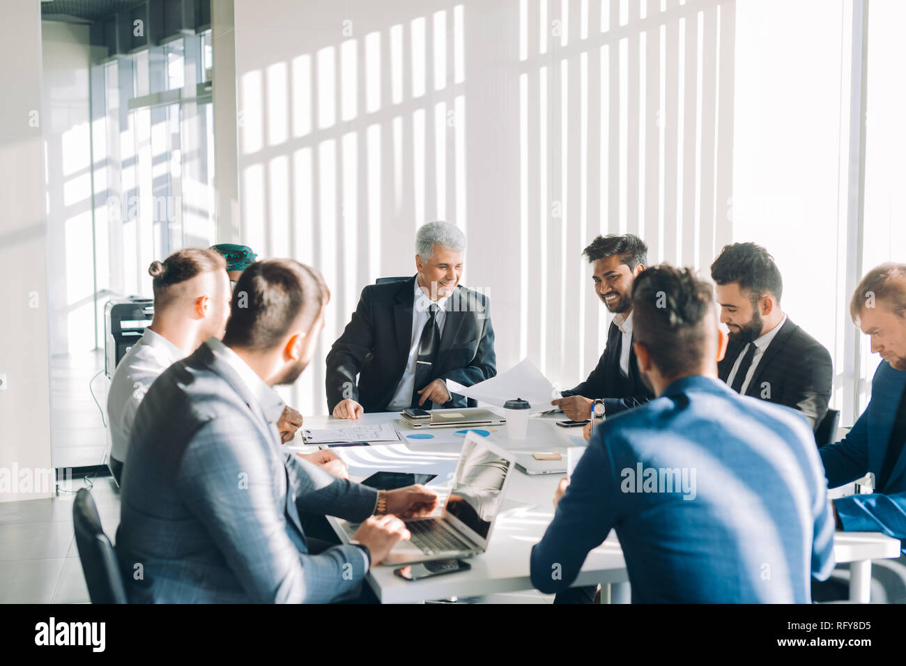 Multiracial male business executives discuss project sitting at ...