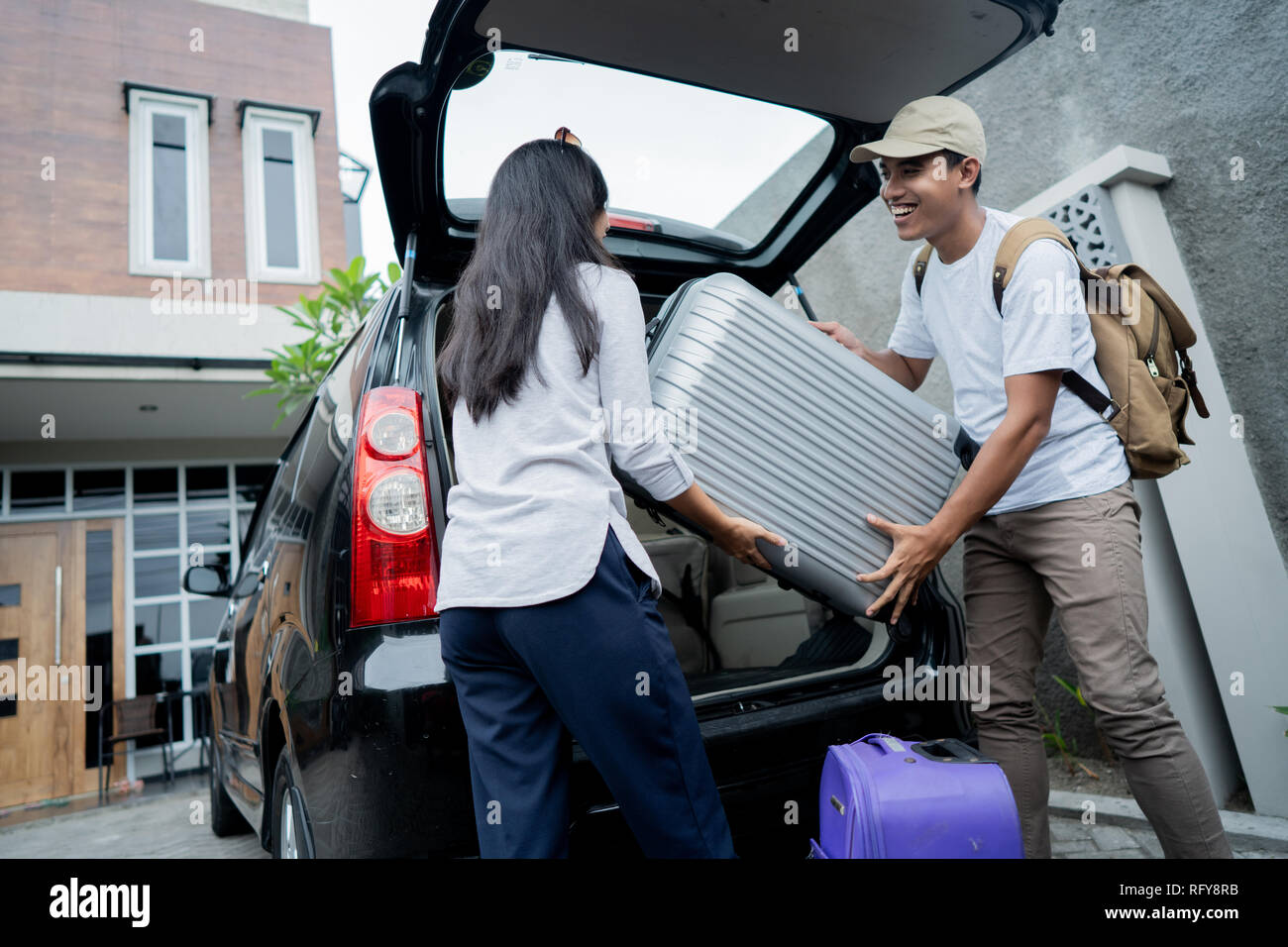 man and woman with their suitcase put in the car trunk Stock Photo - Alamy