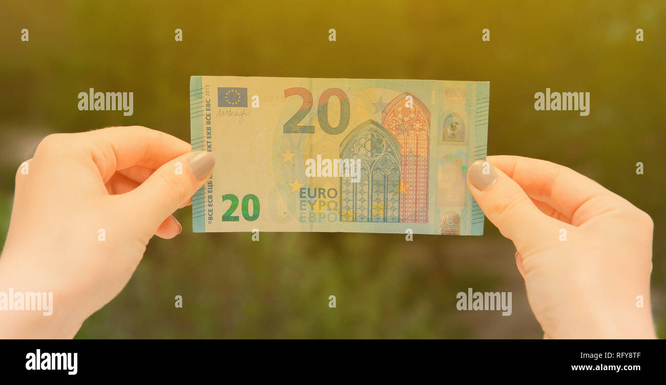 Hands holding 20 euro banknote on the green background. Check euro for ...