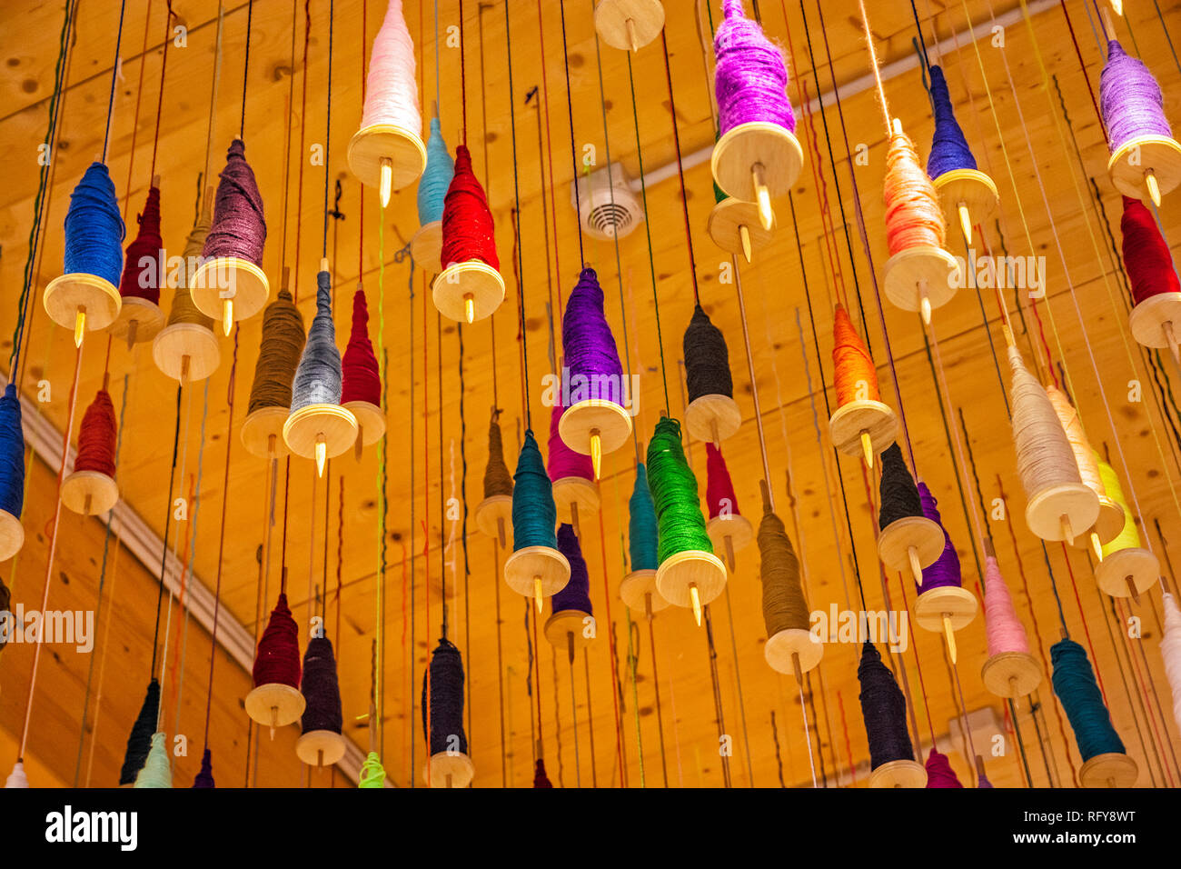Holders with colored wool thread hang from the wooden ceiling ...