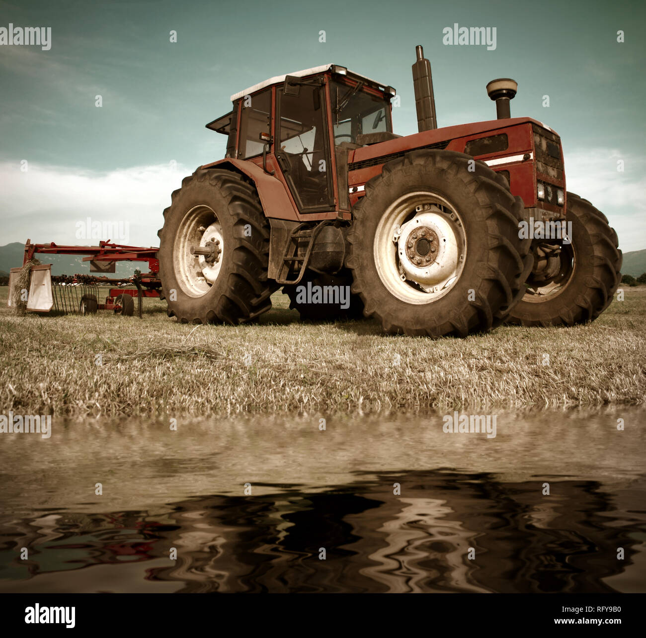 Tractor on field near water pond Stock Photo - Alamy