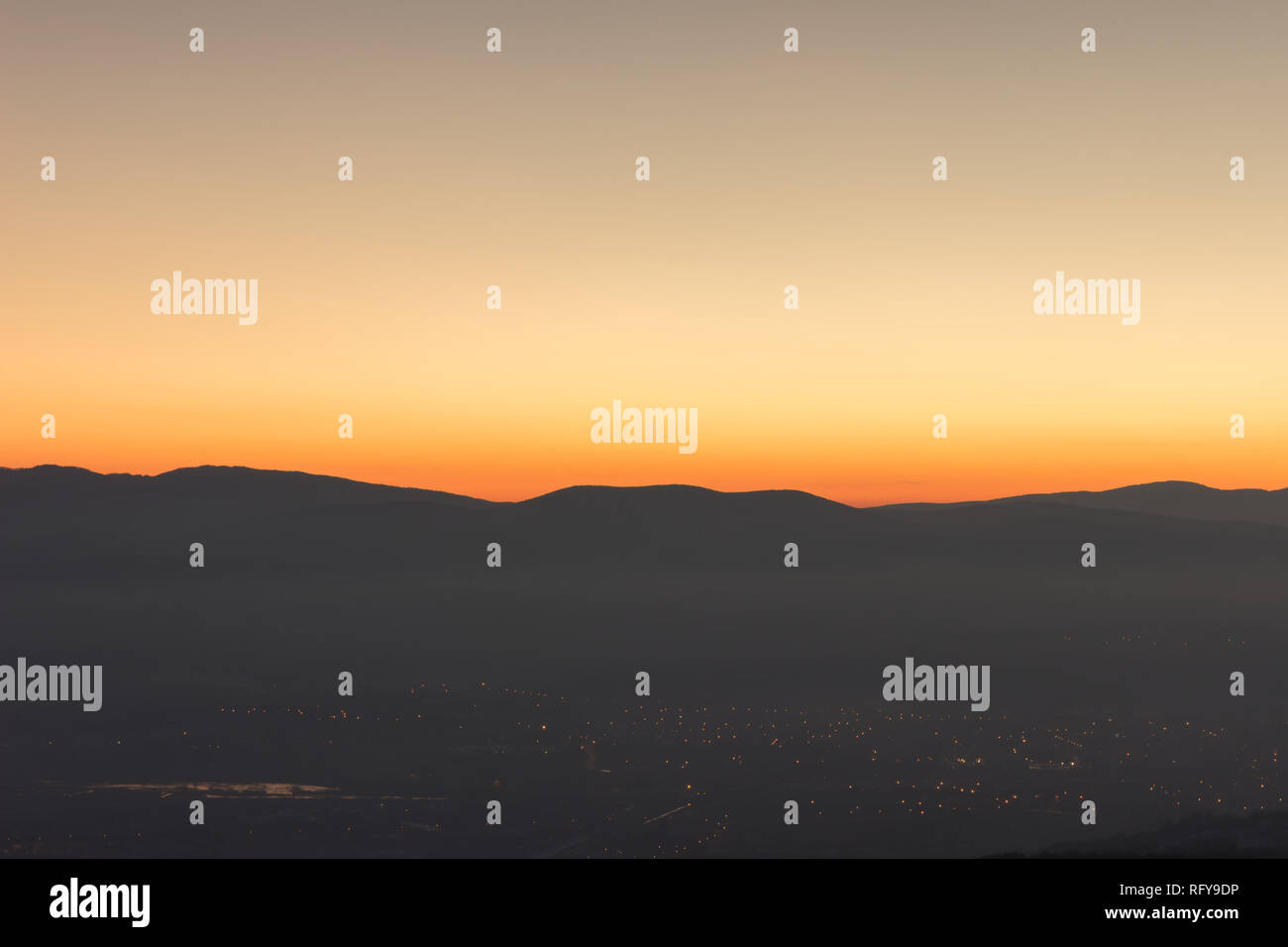 Mountain silhouettes, desaturated cityscape with night city lights and ...