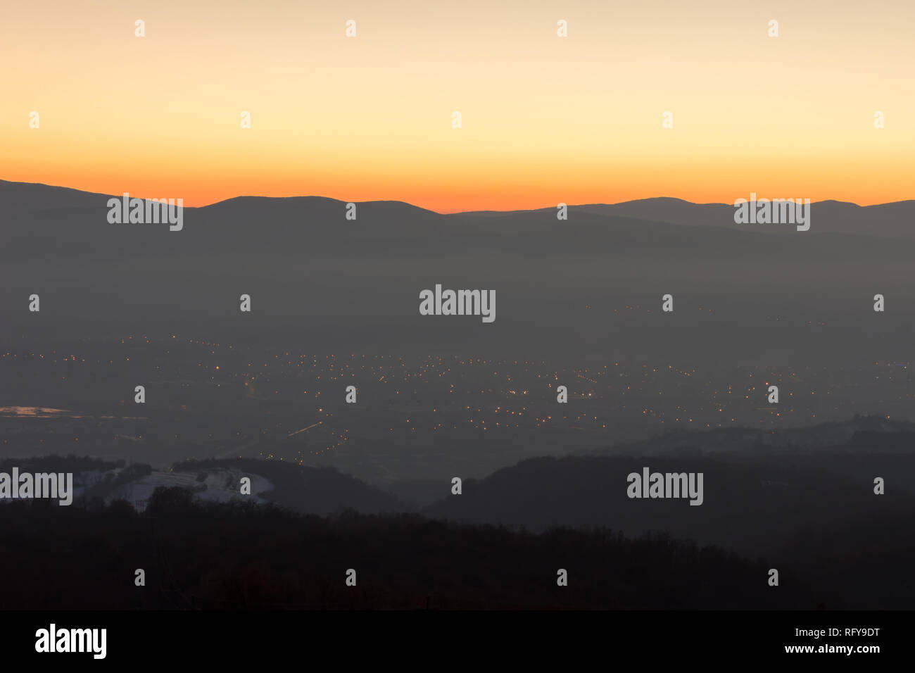 Mountain silhouettes, desaturated cityscape with night city lights and ...