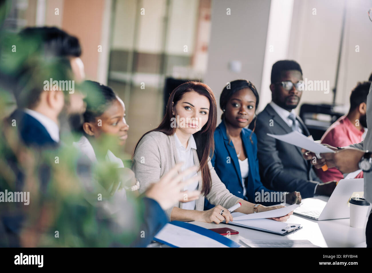 Mixed race people listening to presentation sitting in row at boardroom ...