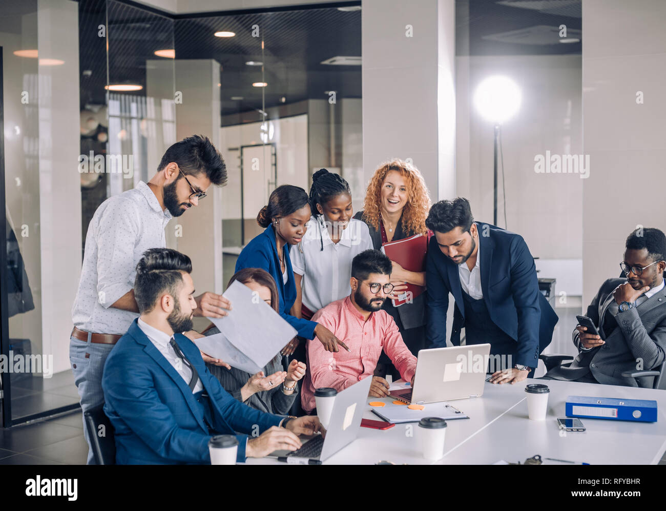 Young multi-ethnic work team exchanges ideas gathering around laptop ...