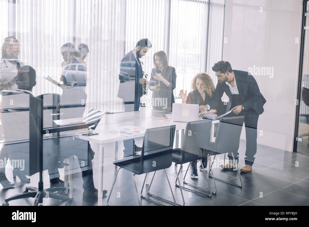 Diverse smiling businesspeople having conversation standing together at ...