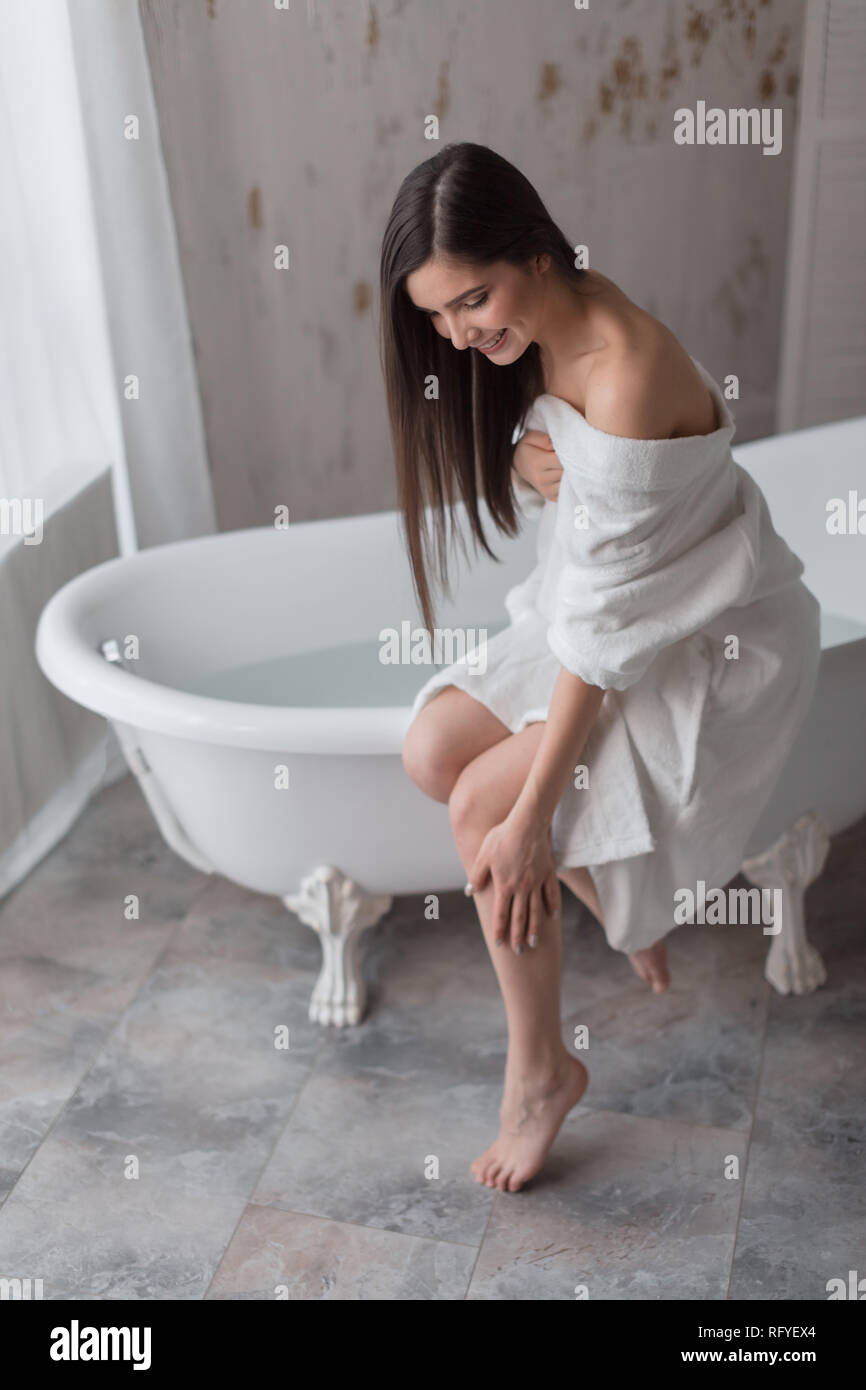 Young Woman Partially Dressed In Robe Taking Care Of Her Legs After