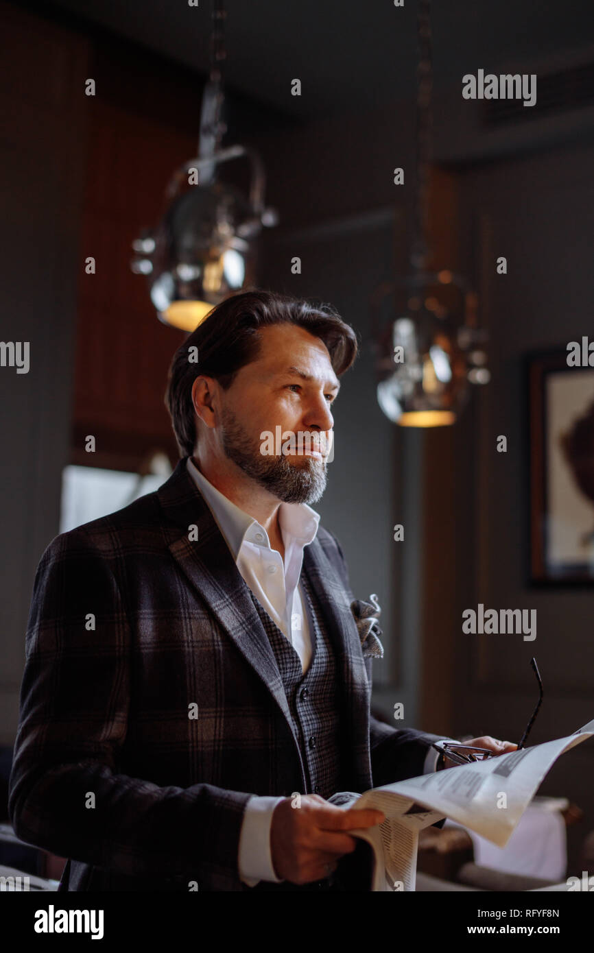 Well-dressed business man reading newspaper in indoor restaurant Stock ...