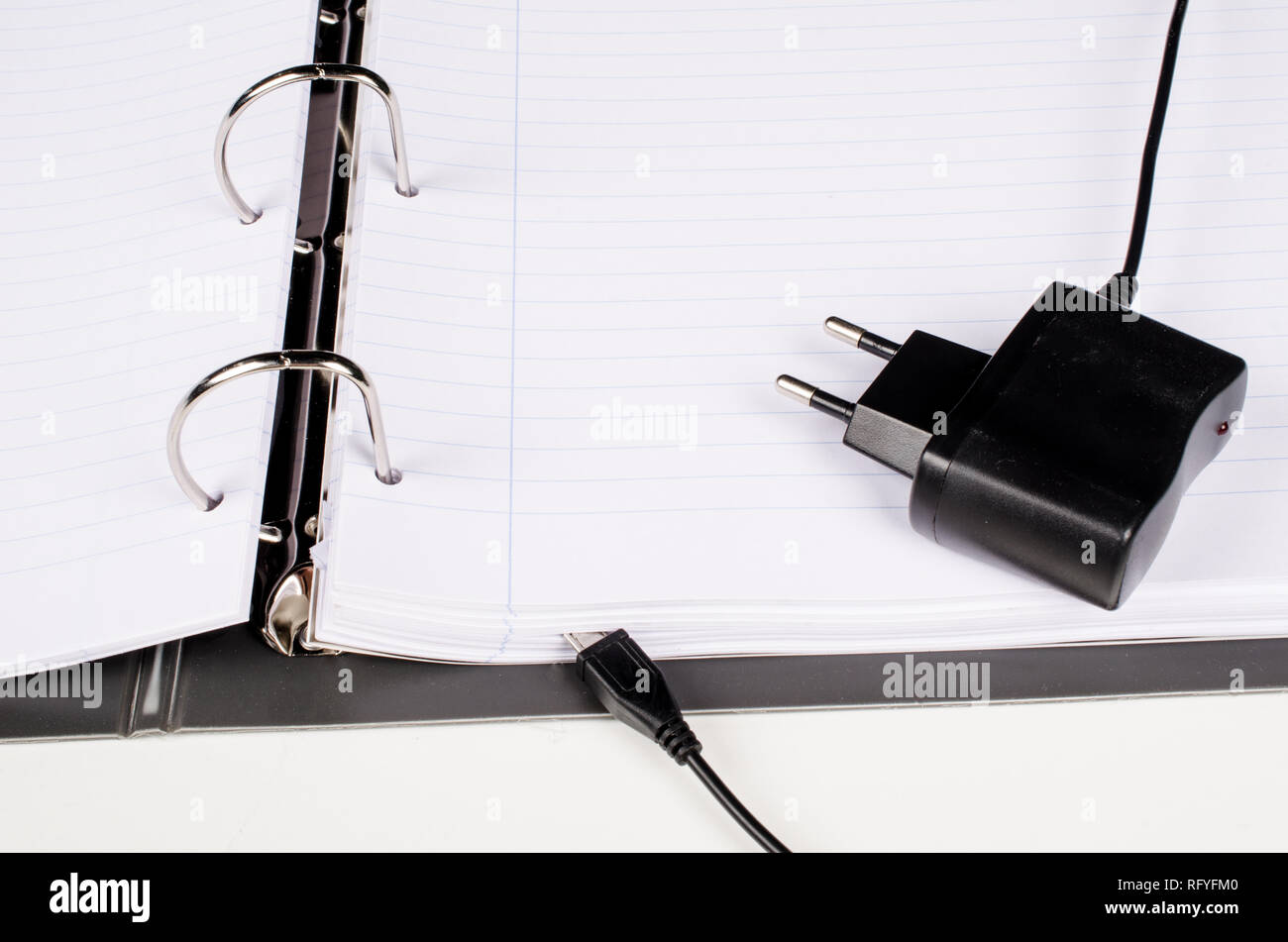 Paper notebook connected to a usb charger, a concept of analog vs ...