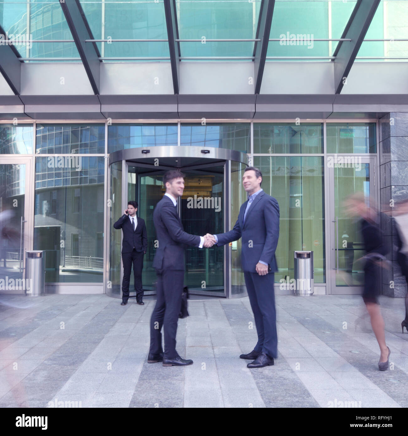 Business people shaking hands, finishing up a meeting outside office ...