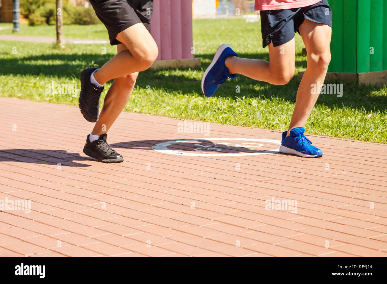 legs of men running in a sports competition on sunny summer morning ...