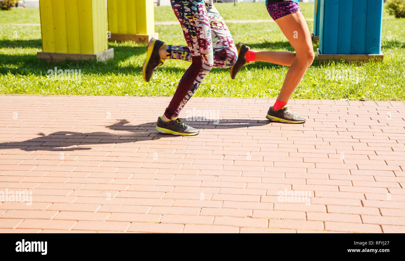 legs of girls running in a sports competition on sunny summer morning ...