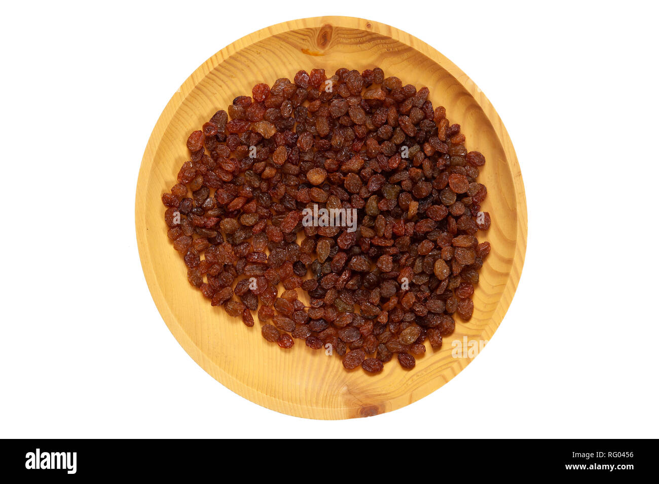 Brown raisins in a wooden pine plate on a white isolated background ...