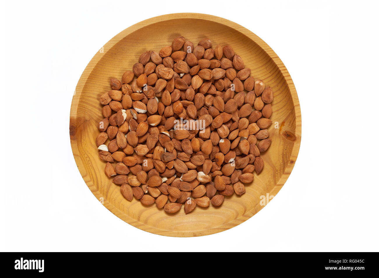 Peeled apricot pits in a wooden pine plate on a white isolated ...