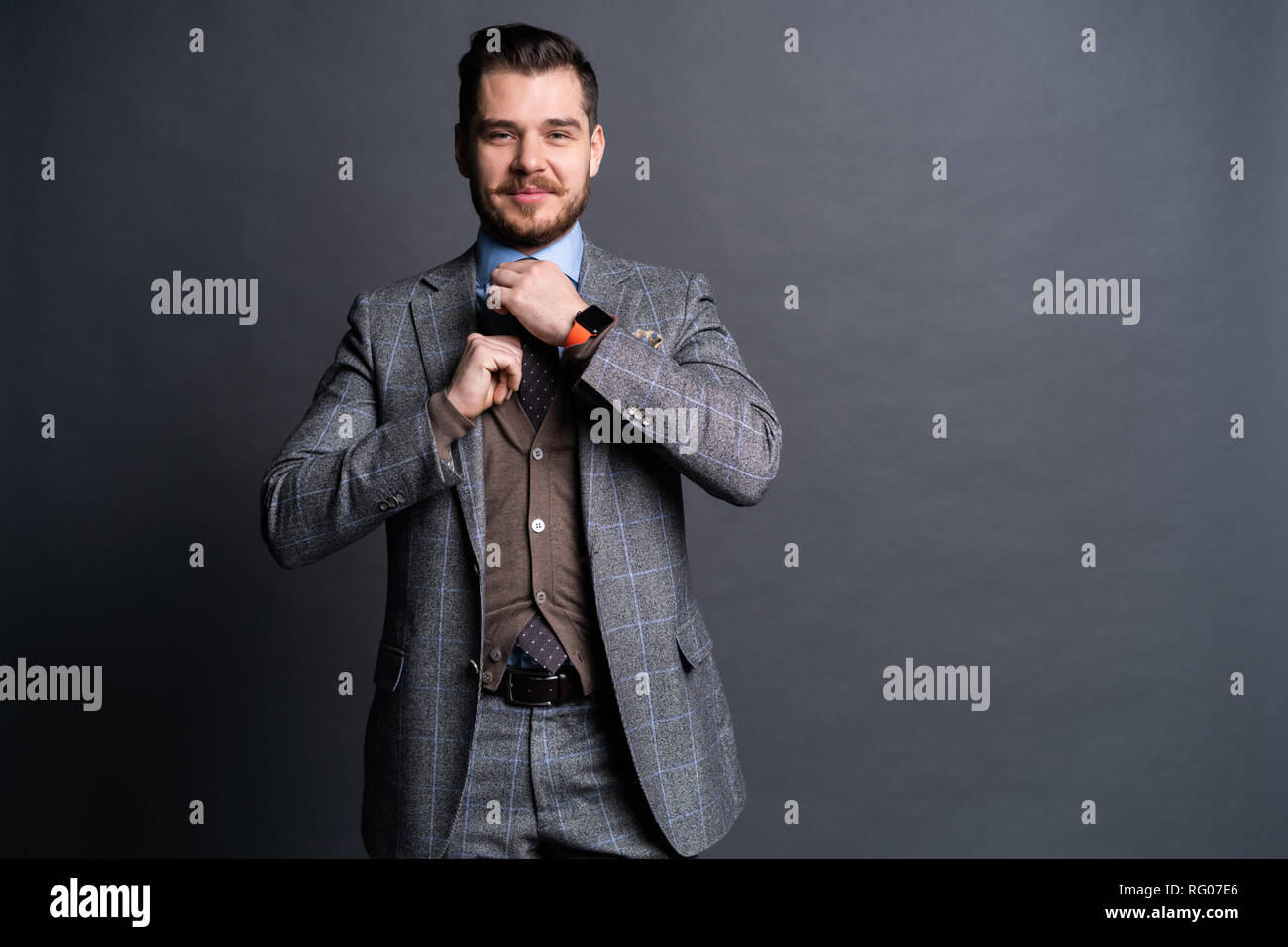 A confident elegant handsome young man standing in front of a grey ...