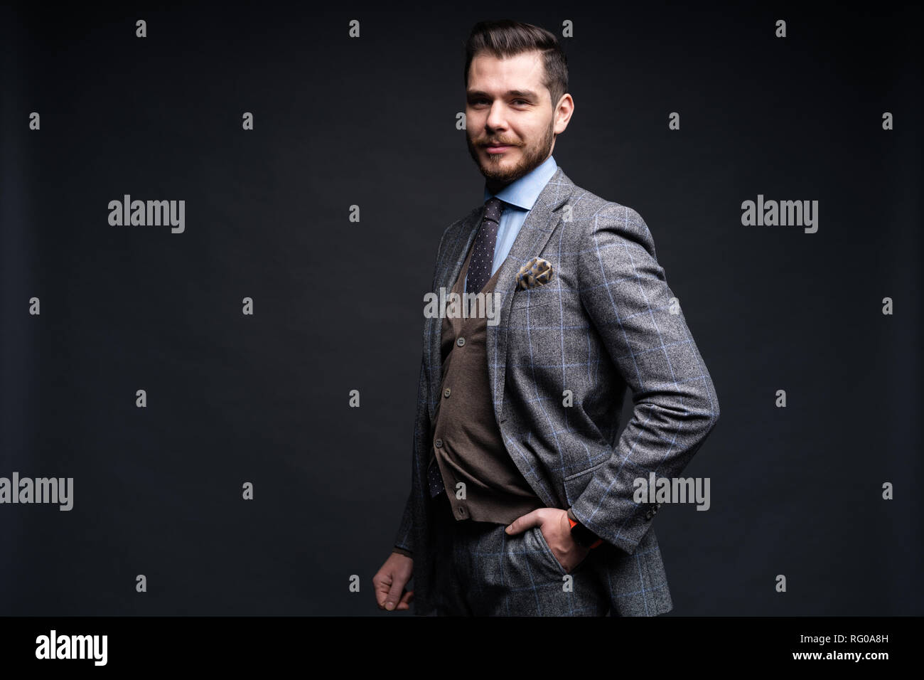 A confident elegant handsome young man standing in front of a black ...