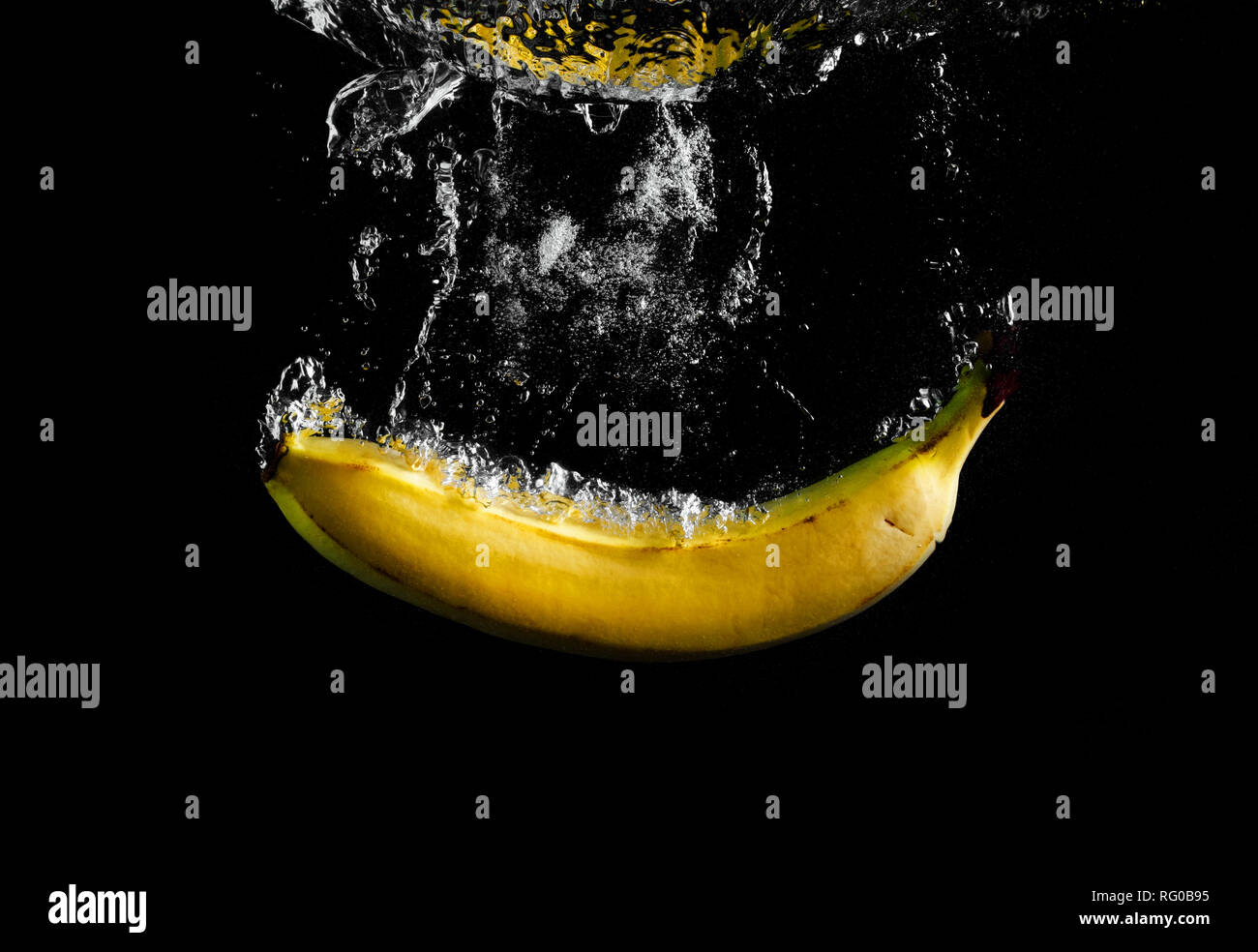 Banana falling in water with splash on black background Stock Photo - Alamy