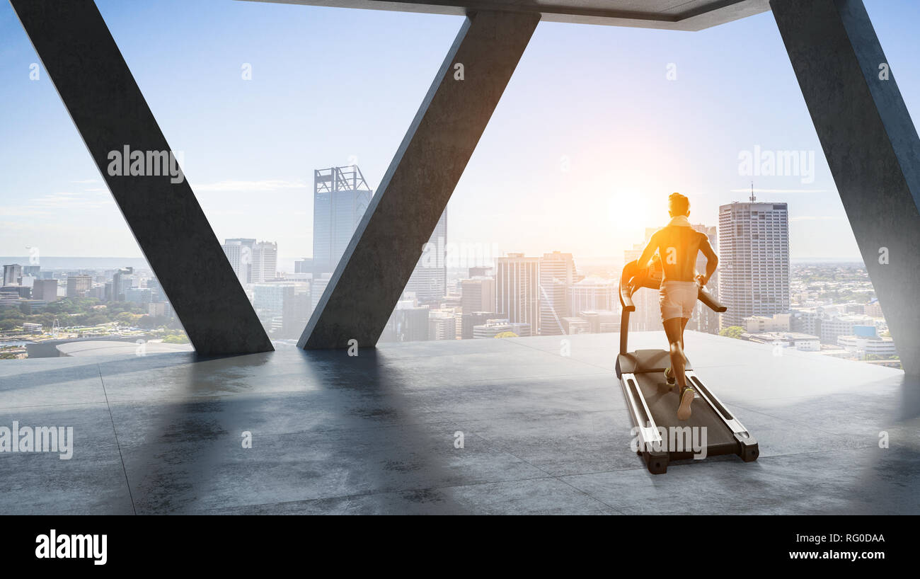 Back view of man athlete running on treadmill. Mixed media Stock Photo ...